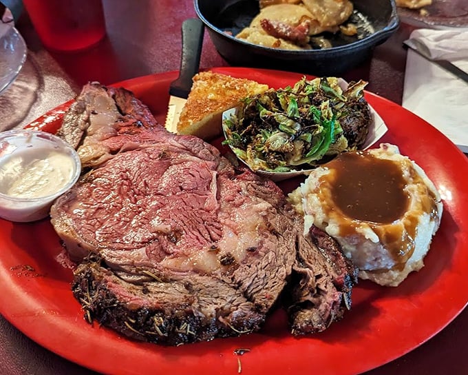 Prime rib that's been kissed by smoke and time, resting majestically on a plate that can barely contain its magnificence.
