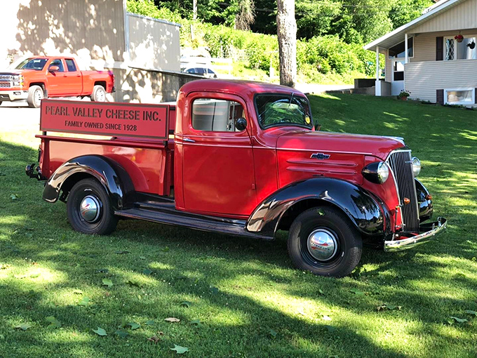 A vintage delivery truck that's seen more cheese journeys than most of us have had hot meals. That red paint job matches the building&mdash;branding consistency since way back!