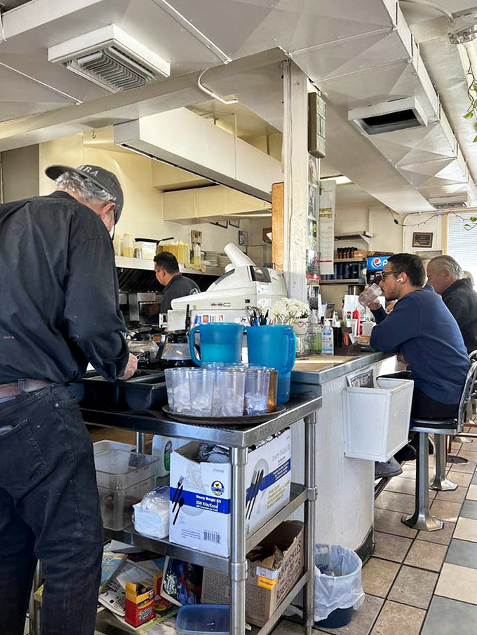 The heart of operations &ndash; where orders are called, coffee is poured, and the rhythm of diner life plays out in three-minute intervals.