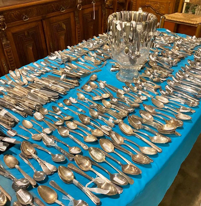 Silver spoons arranged like metallic playing cards—each one a tiny art piece that once stirred sugar into someone's special occasion coffee.