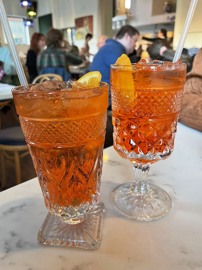 Vibrant Aperol Spritzes in vintage glassware &ndash; Italy's sunset-colored answer to "it's five o'clock somewhere."