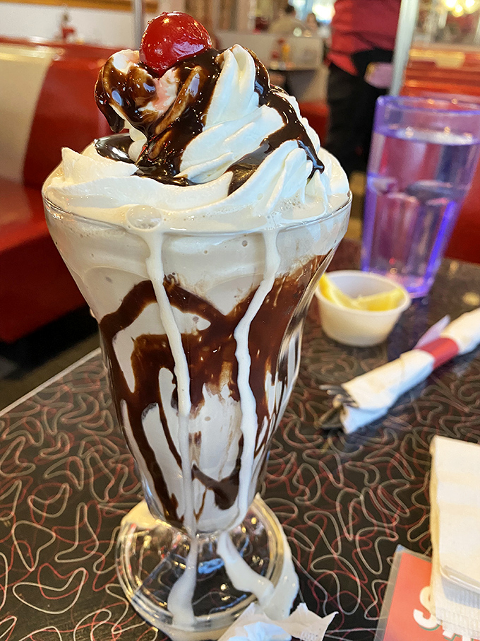 A hot fudge sundae that defies gravity and good sense. The chocolate doesn't just drizzle&mdash;it cascades down the sides like it's making a grand entrance.