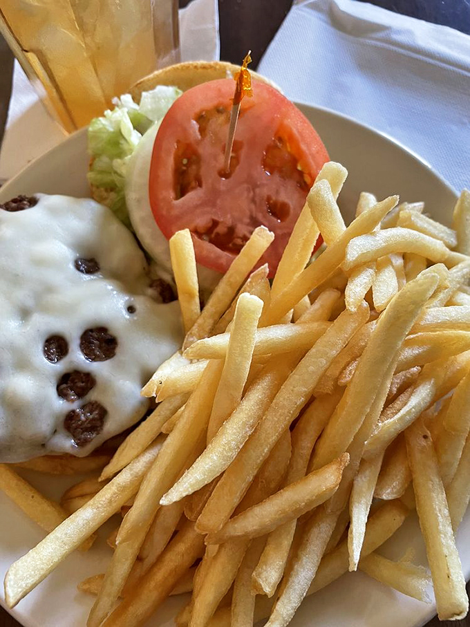 This burger with melted cheese and fresh veggies sits beside a mountain of fries—a plate that says, "You won't need dinner tonight."