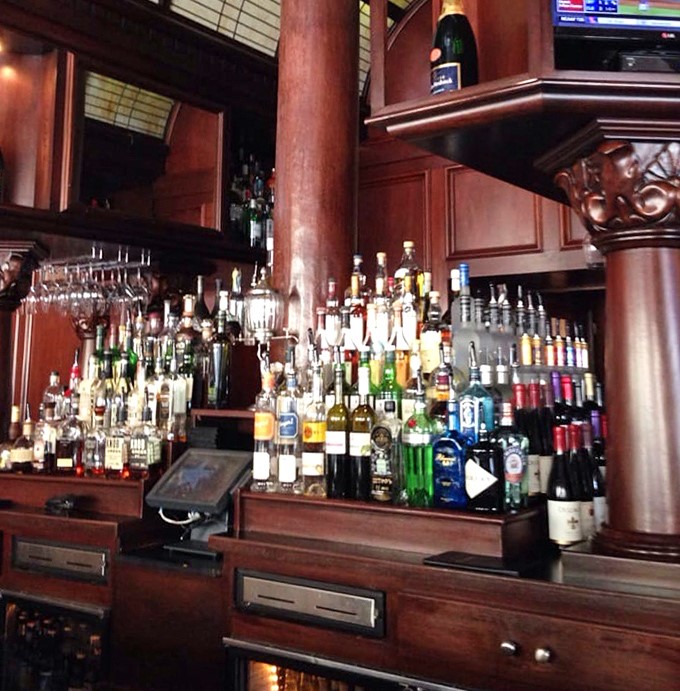 The bar doesn't just stock bottles; it curates liquid possibilities in a mahogany embrace that whispers, "Stay awhile."