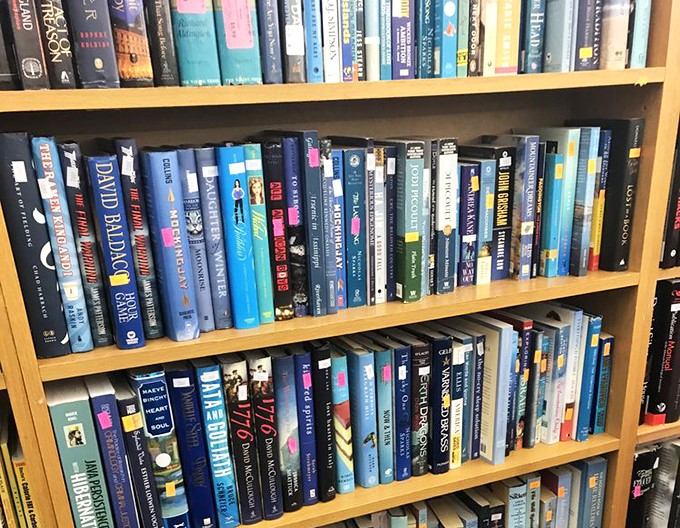 Books stacked like literary dominoes &ndash; dog-eared paperbacks and hardcovers holding stories within stories of previous owners.