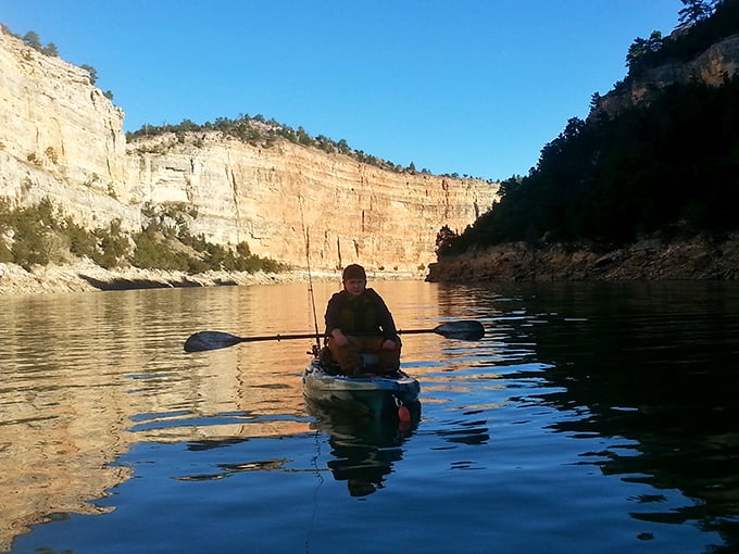 Canyon walls frame a solitary kayaker, creating the kind of peaceful isolation that makes Wyoming's waterways the antithesis of crowded beach resorts.