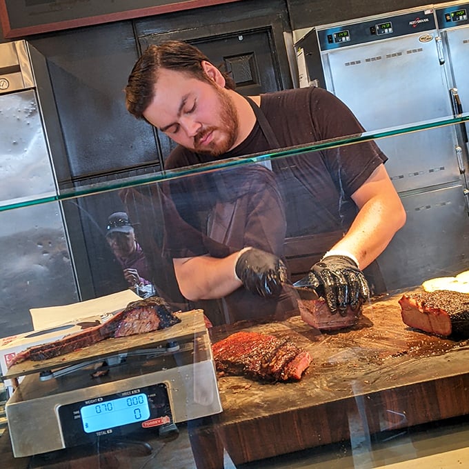 The concentration on this pitmaster's face tells you everything: barbecue isn't just cooking, it's a relationship between meat, fire, and time.