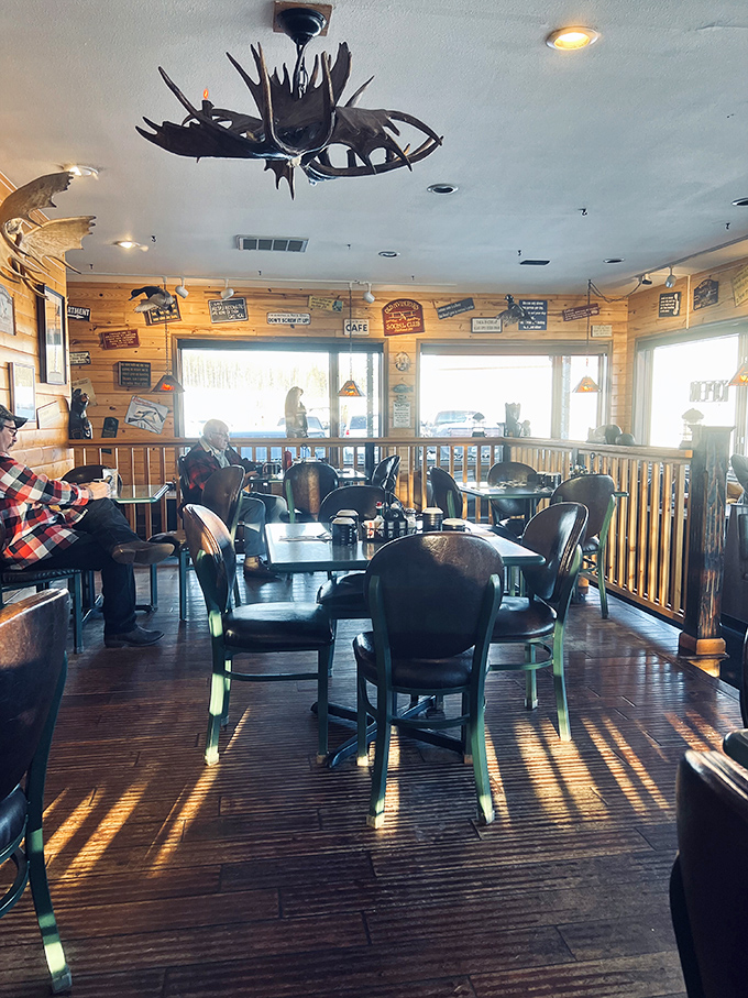 Sunlight streams through windows, casting warm patterns across wooden floors and illuminating antler chandeliers that remind you this is definitely Alaska.