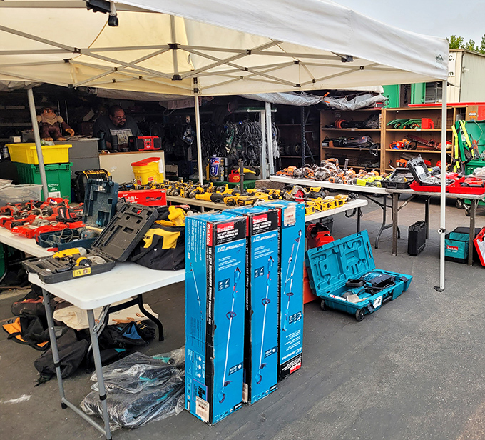 Power tools and equipment spread across tables under a tent, where DIY dreams come true at swap meet prices.