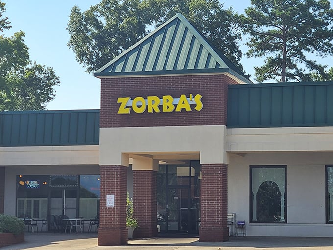 Zorba's bold yellow sign against brick promises a Greek twist on your pizza expectations.