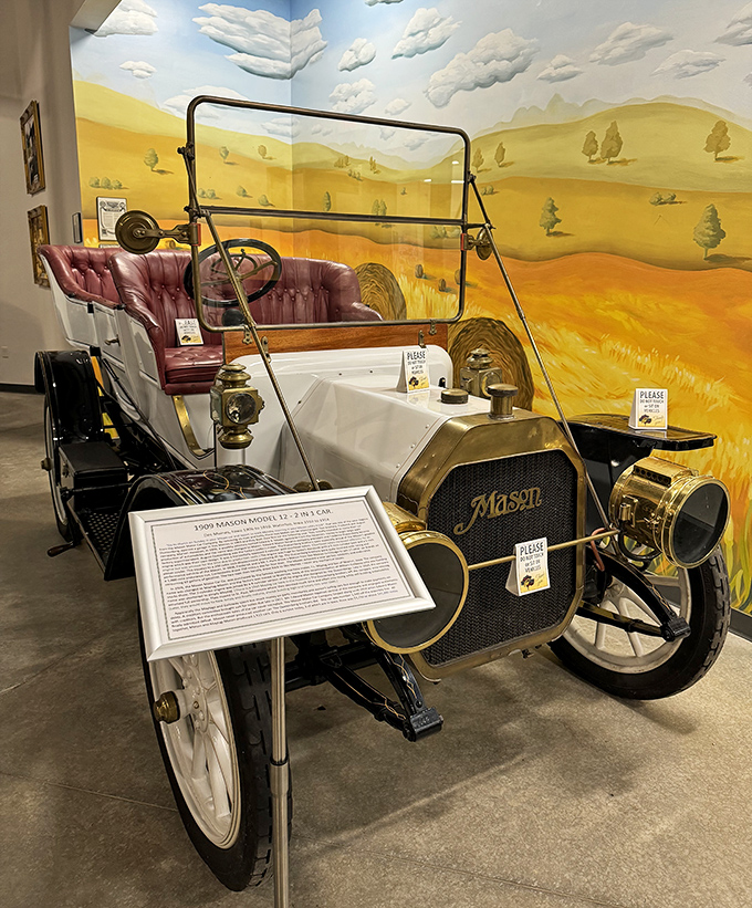 The 1909 Mason Model 12 sits proudly against an Iowa landscape mural, reminding us that these machines once roamed the prairie like mechanical bison.