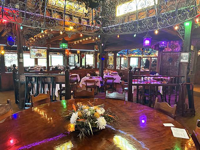 Colorful lights dance across intricate ironwork dividers, creating intimate dining spaces that feel both elegant and whimsical.