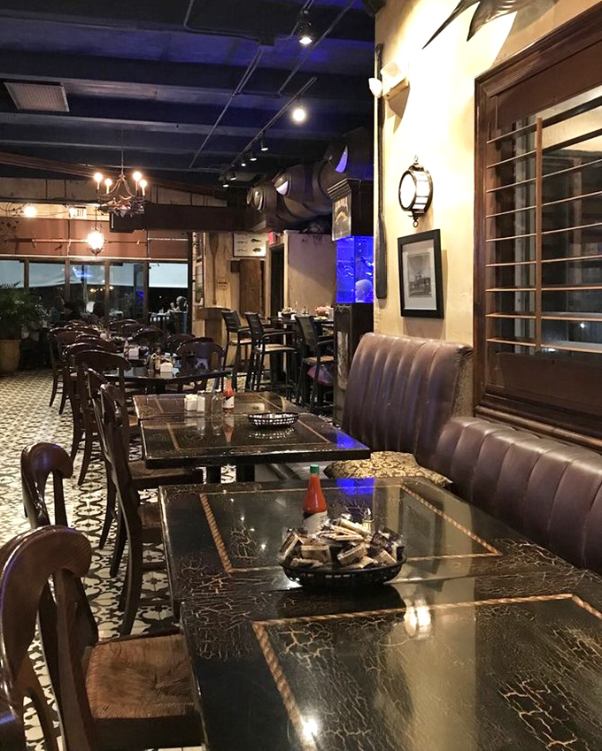 Evening transforms the dining room into a cozy haven where marble tables, warm lighting, and nautical touches create seafood theater.