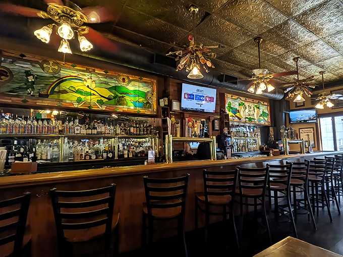 The stained glass backdrop behind the bar catches the light just so, creating an almost church-like reverence for the art of the perfect pour.