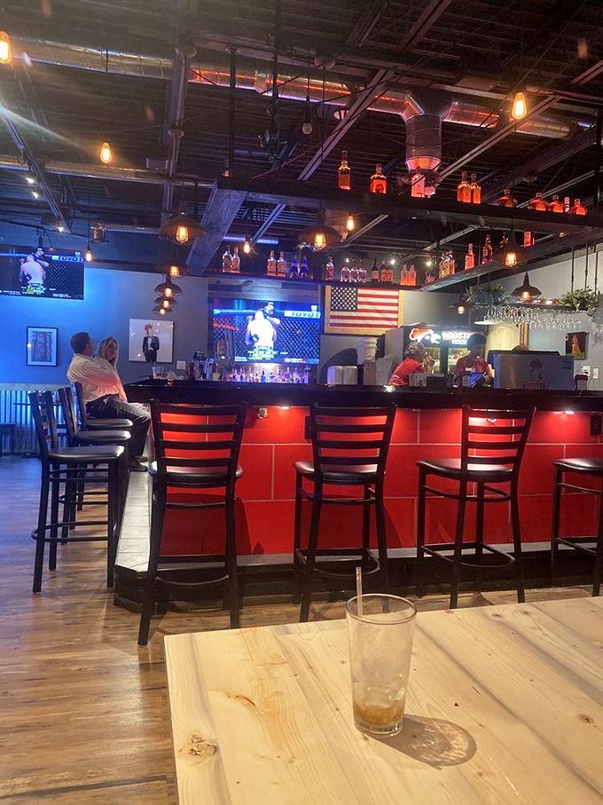 The bar area doesn't just serve drinks&mdash;it creates community. Red stools, multiple screens, and bottles glowing like beacons of hospitality above.