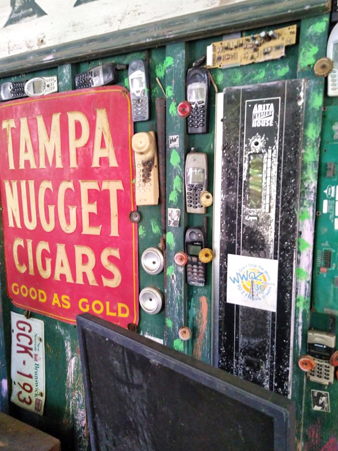 Old cell phones and vintage advertisements create an archaeological timeline of communication technology on this vibrant green wall.