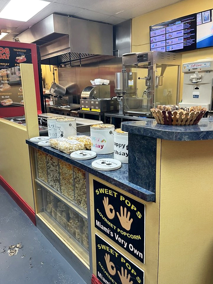 Behind the counter, Sweet Pops gourmet popcorn shares space with hot dog greatness, proving that snack excellence runs in the family.