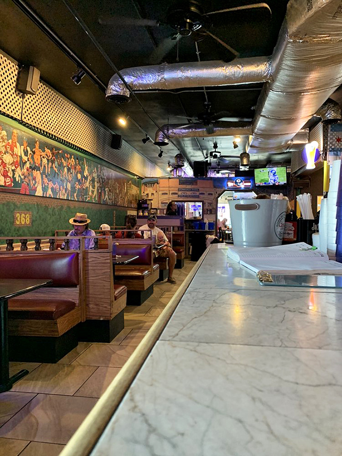 Booth seating with a sports mural backdrop&mdash;where strangers become friends over shared meals and close games together.