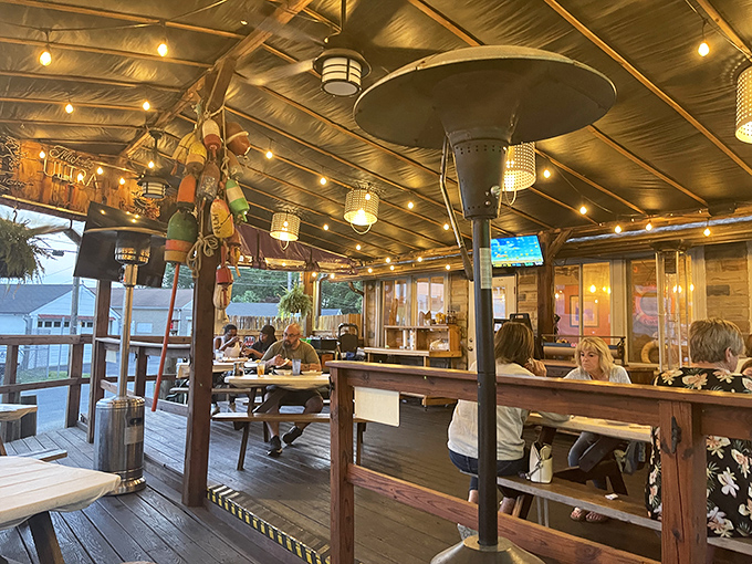 The covered patio offers waterfront dining vibes with colorful buoys dangling overhead like maritime Christmas ornaments.