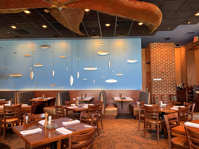 Blue walls adorned with suspended silver fish create an underwater dreamscape where the dining tables become islands in a sea of culinary possibility.