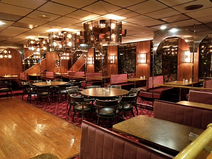 Evening transforms the dining room into a warm sanctuary of wood paneling, soft lighting, and the kind of booths that invite you to settle in for the long haul.