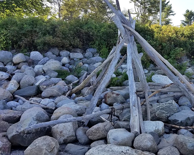 Someone built a driftwood teepee on the rocks, combining childhood creativity with beachcombing skills and impressive architectural ambition. 