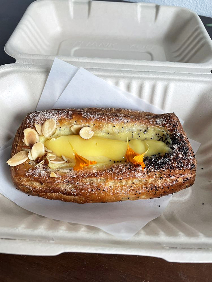 This isn't just a pastry, it's a lemon custard dream wearing a croissant costume, dusted with powdered sugar and topped with almonds.