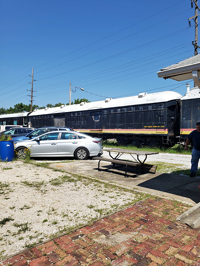 Modern vehicles parked beside vintage rail cars create a timeline of American transportation that speaks volumes without saying a single word.