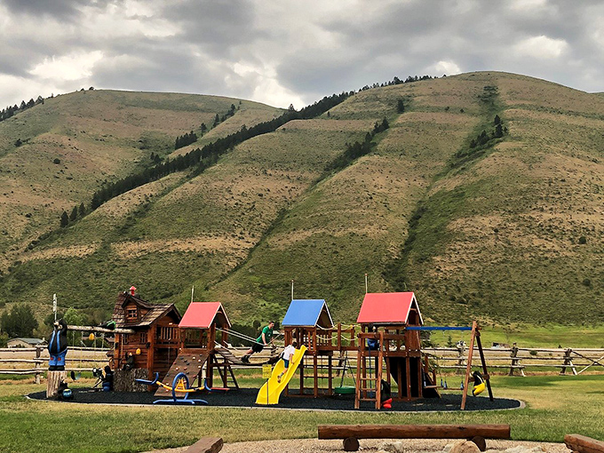 Colorful playground structures sit beneath imposing foothills, where children's laughter echoes against nature's magnificent backdrop.