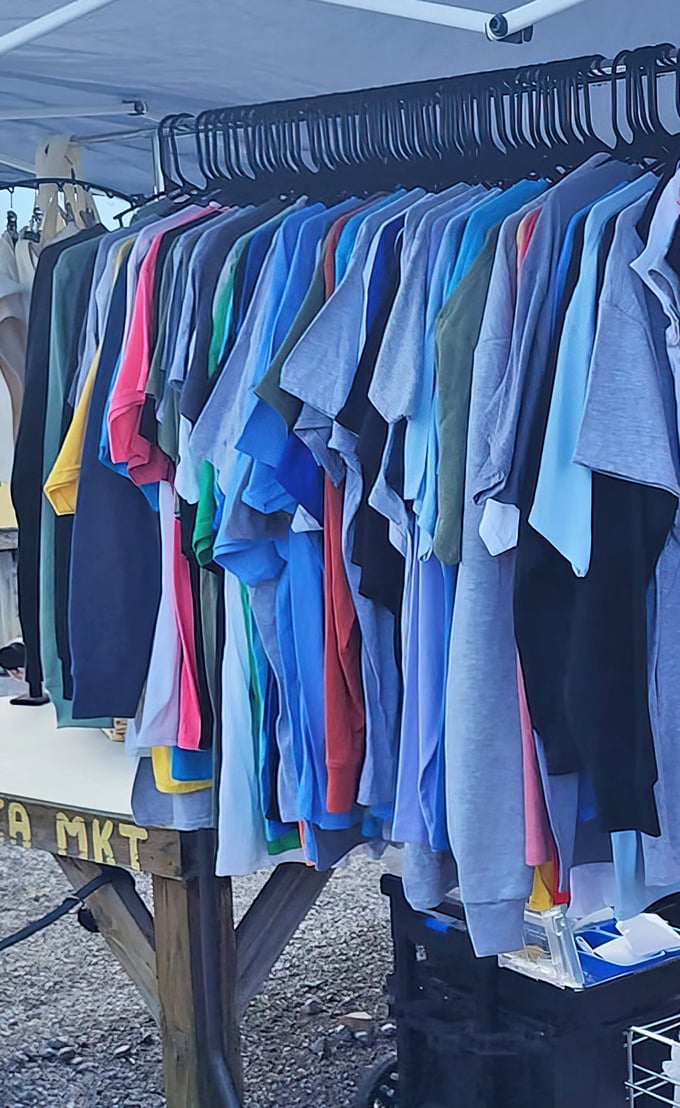 A rainbow of t-shirts hanging like someone organized the world's most casual and affordable fashion show display.
