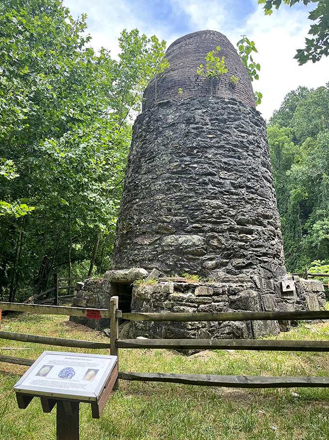 The ancient stone furnace rises like a monument to industrial ingenuity. This historic structure once roared with fire, now stands in peaceful slumber.