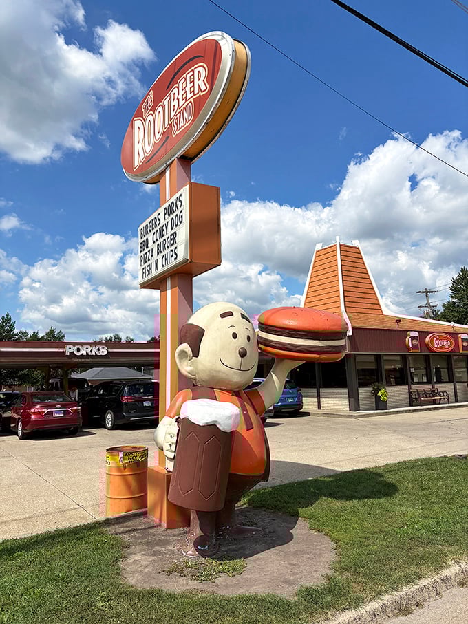 The Rootbeer Stand's retro mascot cheerfully hoists a burger, embodying the timeless appeal of classic American roadside dining.