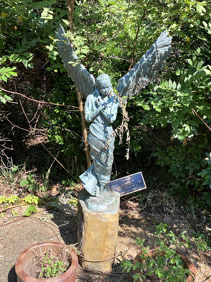 This winged angel statue stands as a peaceful guardian among the foliage. Some art seems to bless the very ground where it stands.
