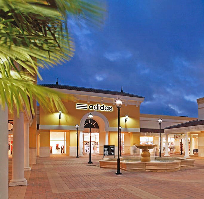 The adidas store stands illuminated against the twilight sky, a temple to athletic aspirations and surprisingly affordable three-stripe fashion.