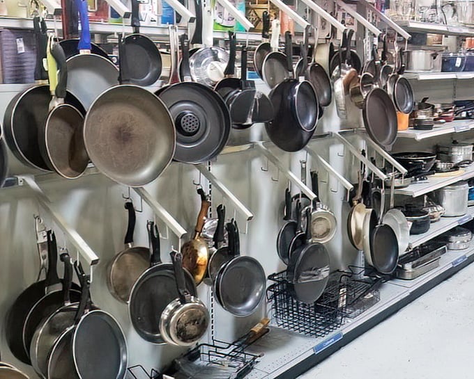 Cookware hanging like metallic stalactites above shelves of culinary potential, ready to equip kitchens with affordable functionality and character.