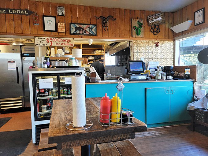 The heart of operations &ndash; where burger magic happens. That "$5 Charge for Whining" sign tells you everything about the caf&eacute;'s delightful personality.