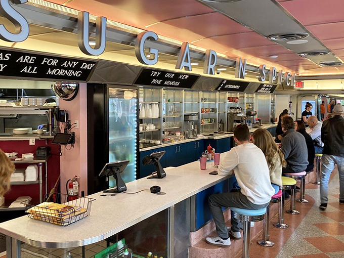 At the counter, where "SUGAR N' SPICE" hovers overhead like a promise, breakfast dreams come true one plate at a time.