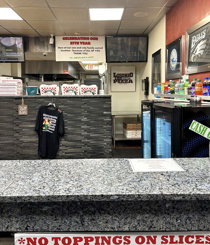 The command center of pizza simplicity&mdash;where Philly sports memorabilia meets the gospel truth of "NO TOPPINGS ON SLICES" in granite-etched glory.