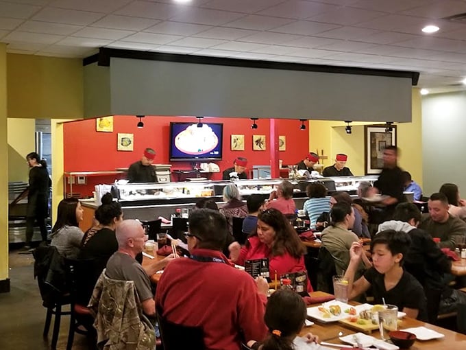 A bustling dining room where the sushi chefs work their magic behind the counter. Good food brings people together better than any social media platform.