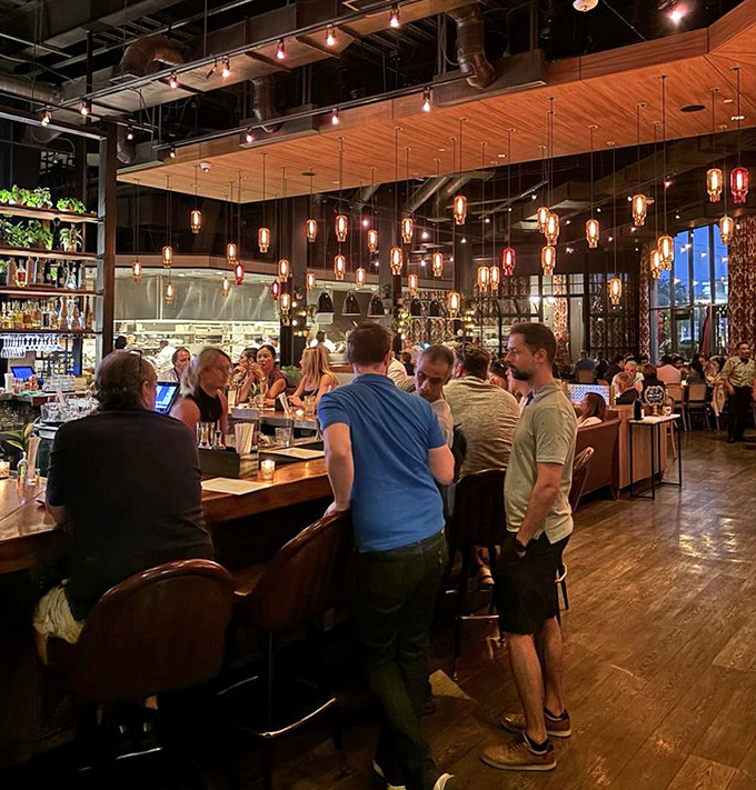 The bar area glows with amber lighting and plush seating – like your stylish friend's living room, if your friend were a master mixologist.