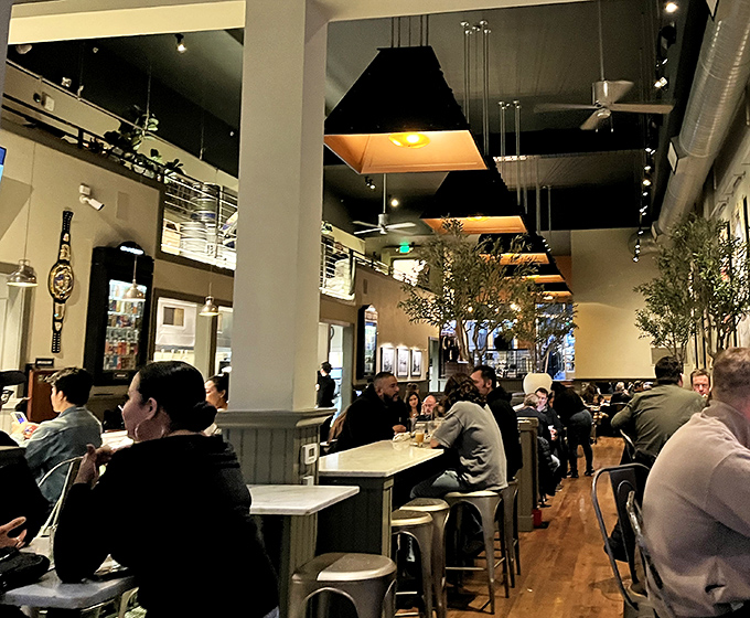 The dining room buzzes with the energy of happy eaters. Those indoor trees bring a touch of nature to complement the feast of flavors on every table.