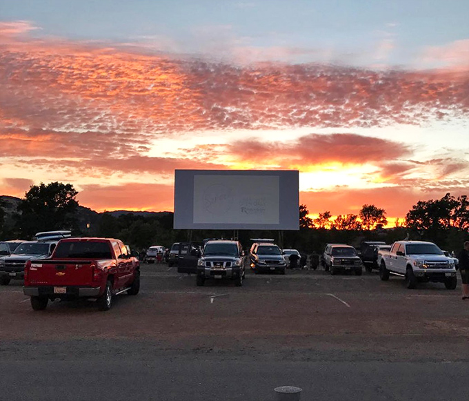 The modern drive-in experience: a perfect grid of trucks and SUVs facing the silver screen, headlights off but excitement fully illuminated.