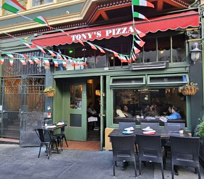 Italian flags flutter above outdoor tables, transforming a slice of San Francisco sidewalk into a little corner of Naples. Pizza diplomacy at its finest.