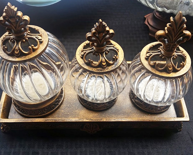 Ornate glass jars with golden lids add fancy storage that makes even cotton balls look sophisticated somehow.