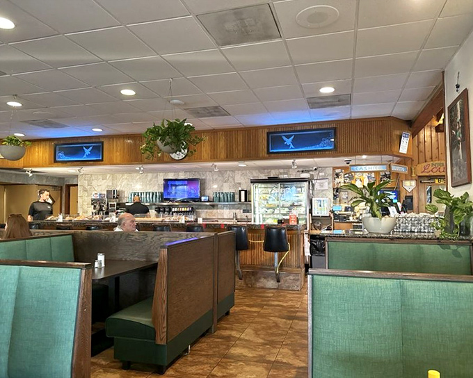 The counter and booth section offers front-row seats to the breakfast theater. Green accents and wood paneling set the classic diner stage.