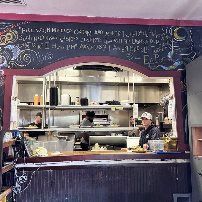Behind the kitchen pass, a Poe quote looms above busy cooks. Even in the heat of service, literary inspiration finds its place.