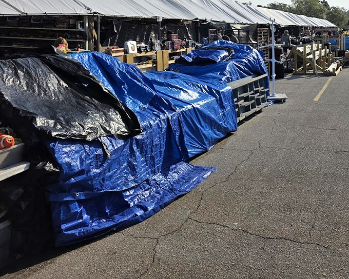 Vendors prepare for the day under blue tarps – the calm before the storm of bargain hunters descends upon their carefully arranged wares.