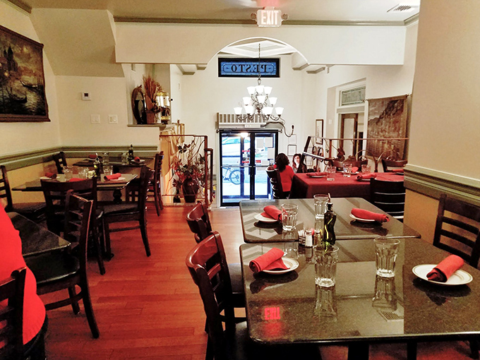 Red napkins pop against dark tables in this dining room that balances old-world charm with contemporary comfort.