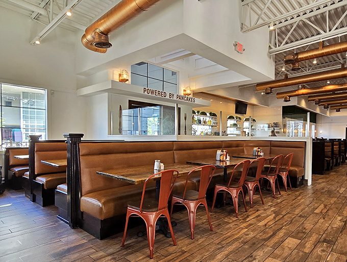 Leather banquettes and copper chairs aren't just seating&mdash;they're front-row tickets to the breakfast show. The "POWERED BY PANCAKES" sign reminds you why you came.