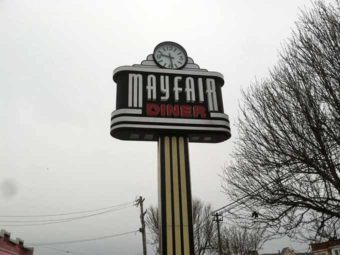 The iconic Mayfair Diner sign stands tall against the Philadelphia sky, complete with a clock because time stops when you're enjoying a perfect meal.